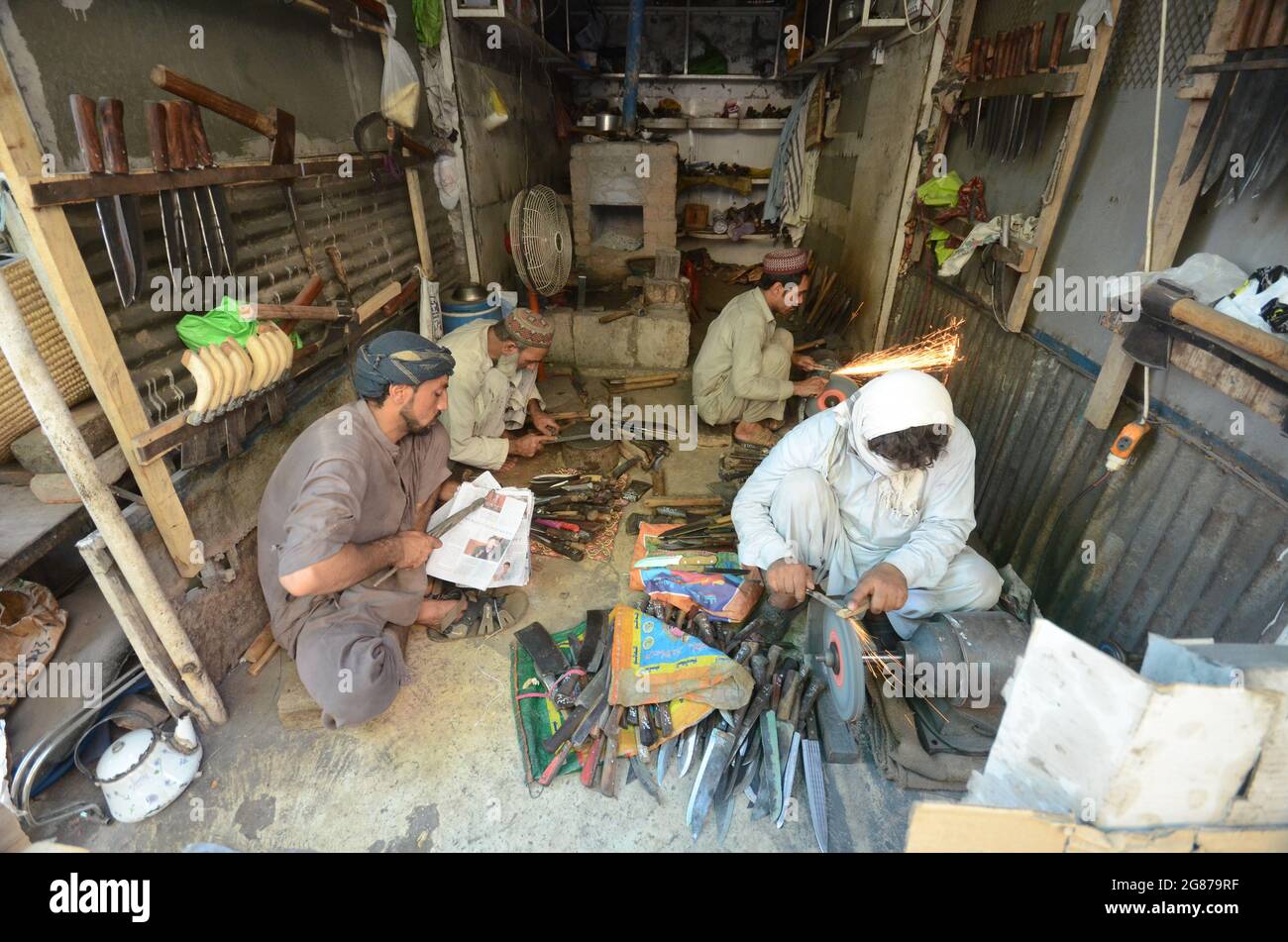 Peshawar, Pakistan. 17th July, 2021. A Pakistani vendor sharpen axe ...