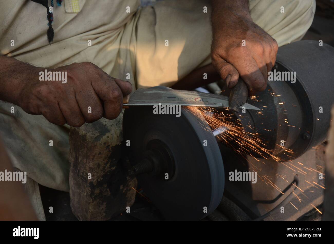 Peshawar, Pakistan. 17th July, 2021. A Pakistani vendor sharpen axe ...