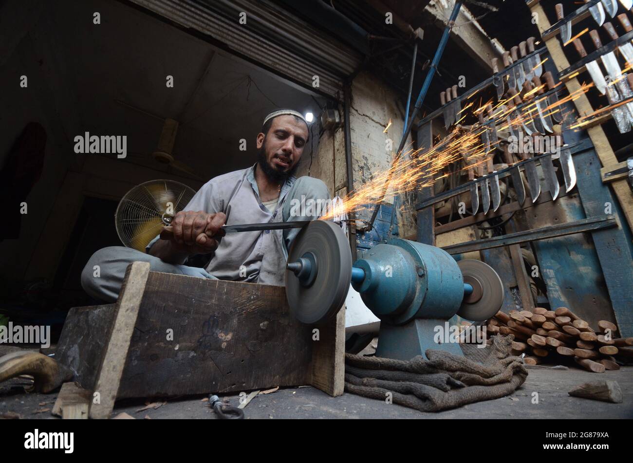 A Pakistani vendor sharpen axe which will be used to animal ...