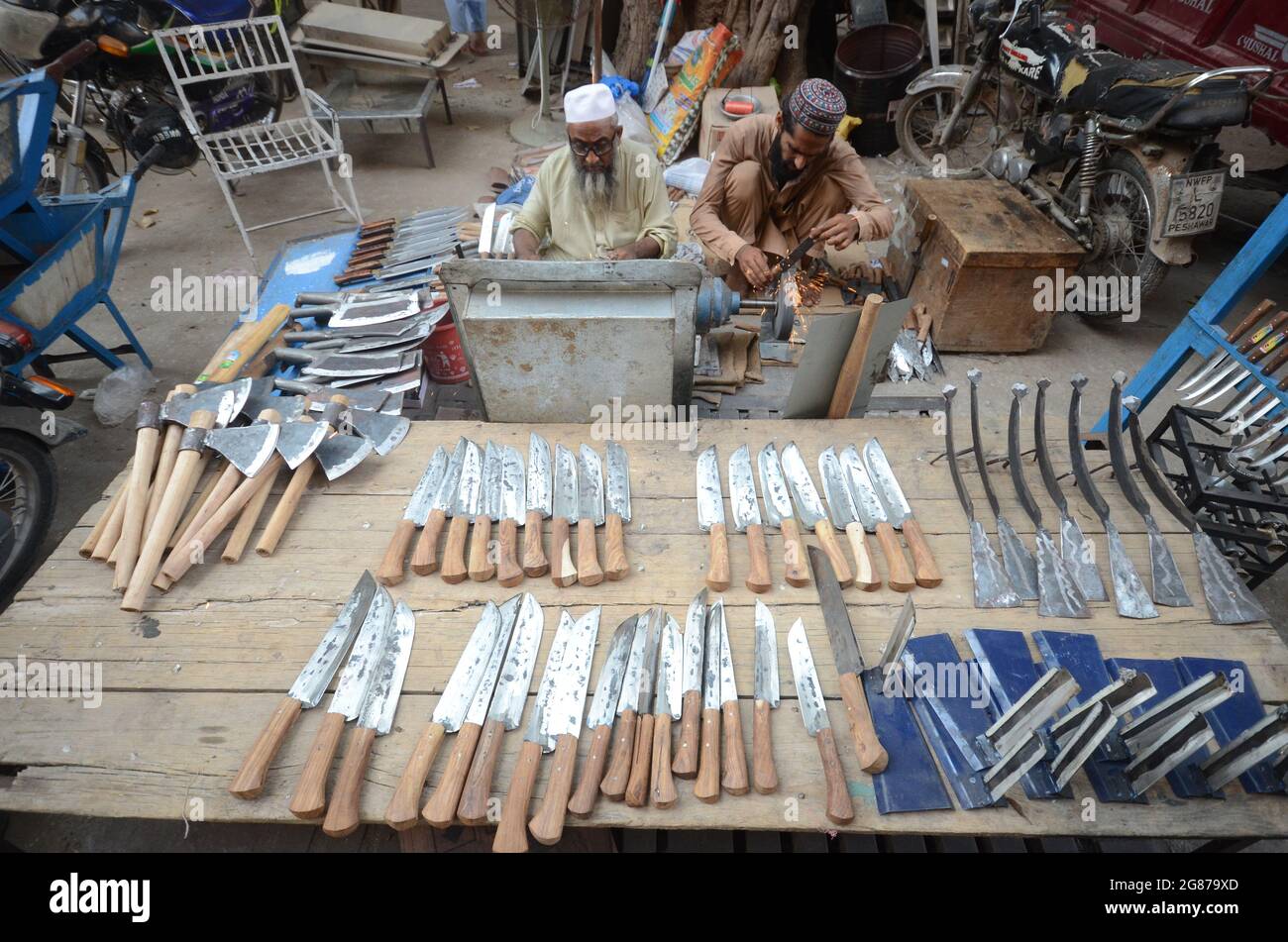Peshawar, Pakistan. 17th July, 2021. A Pakistani vendor sharpen axe ...