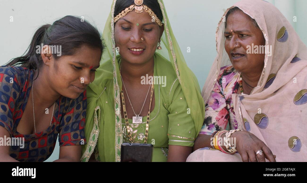 Three generations of South Asian women in traditional clothing using a ...
