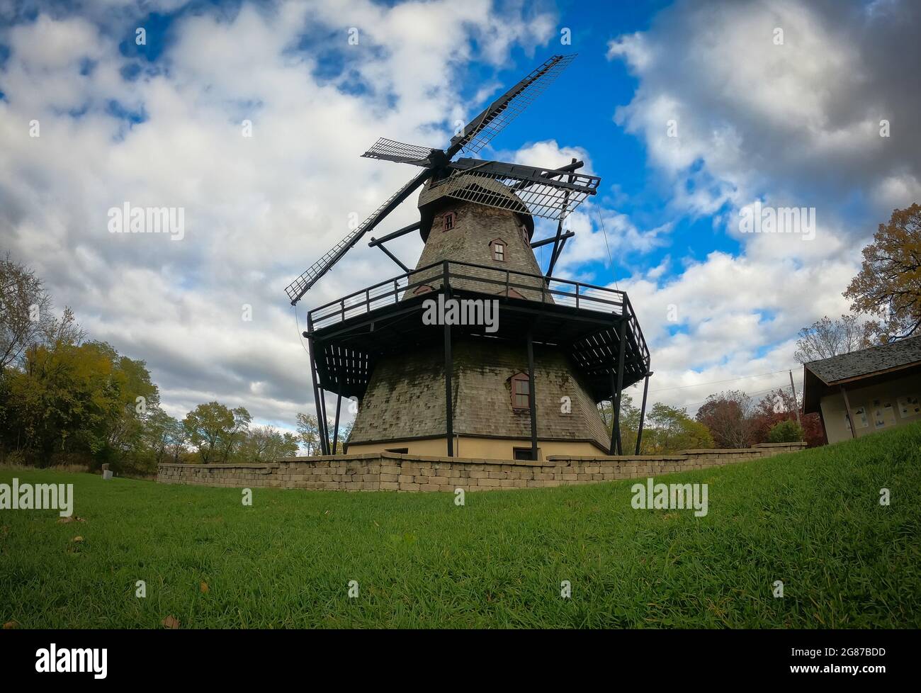 Old windmill on a farm field covered in greenery under a blue cloudy ...