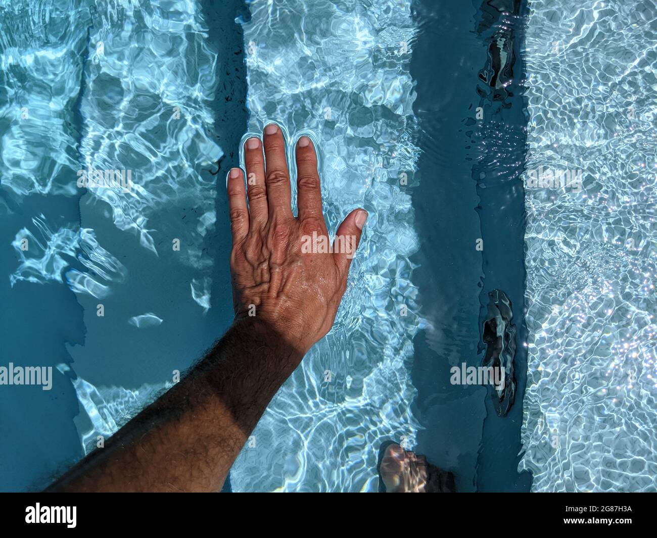 Male left hand on rippling pool water surface Stock Photo - Alamy