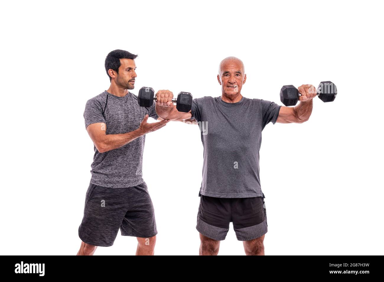 Old man with a personal trainer is conducting a fitness workout. On an ...