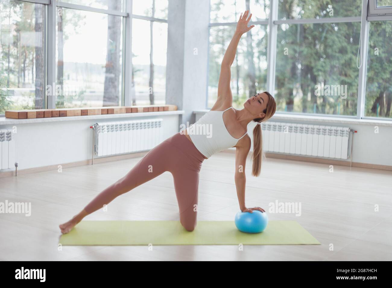 Young woman working out with a ball indoors on green mat Stock Photo ...