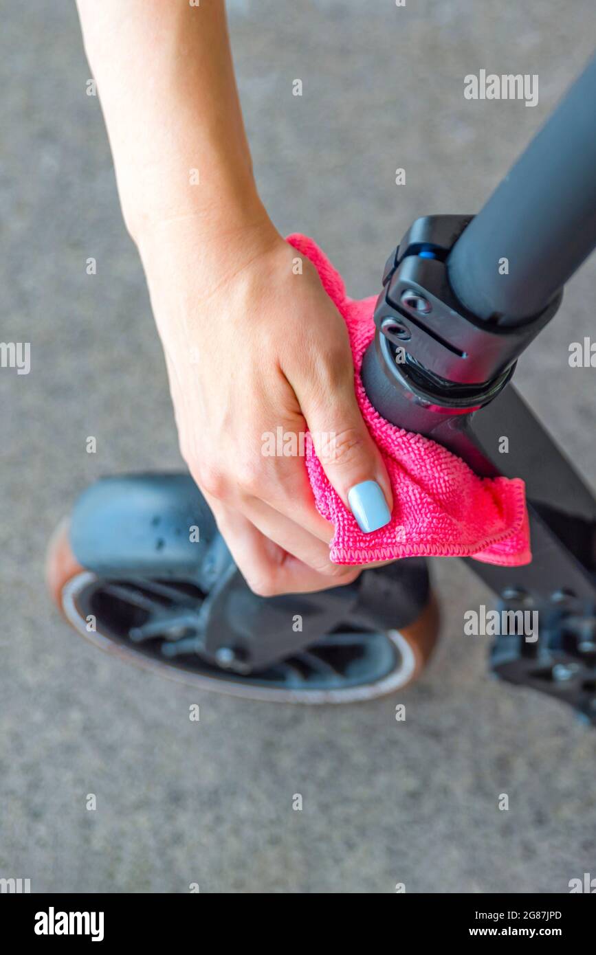 Cleaning or washing the scooter. Electric scooter care. A woman wipes a ...