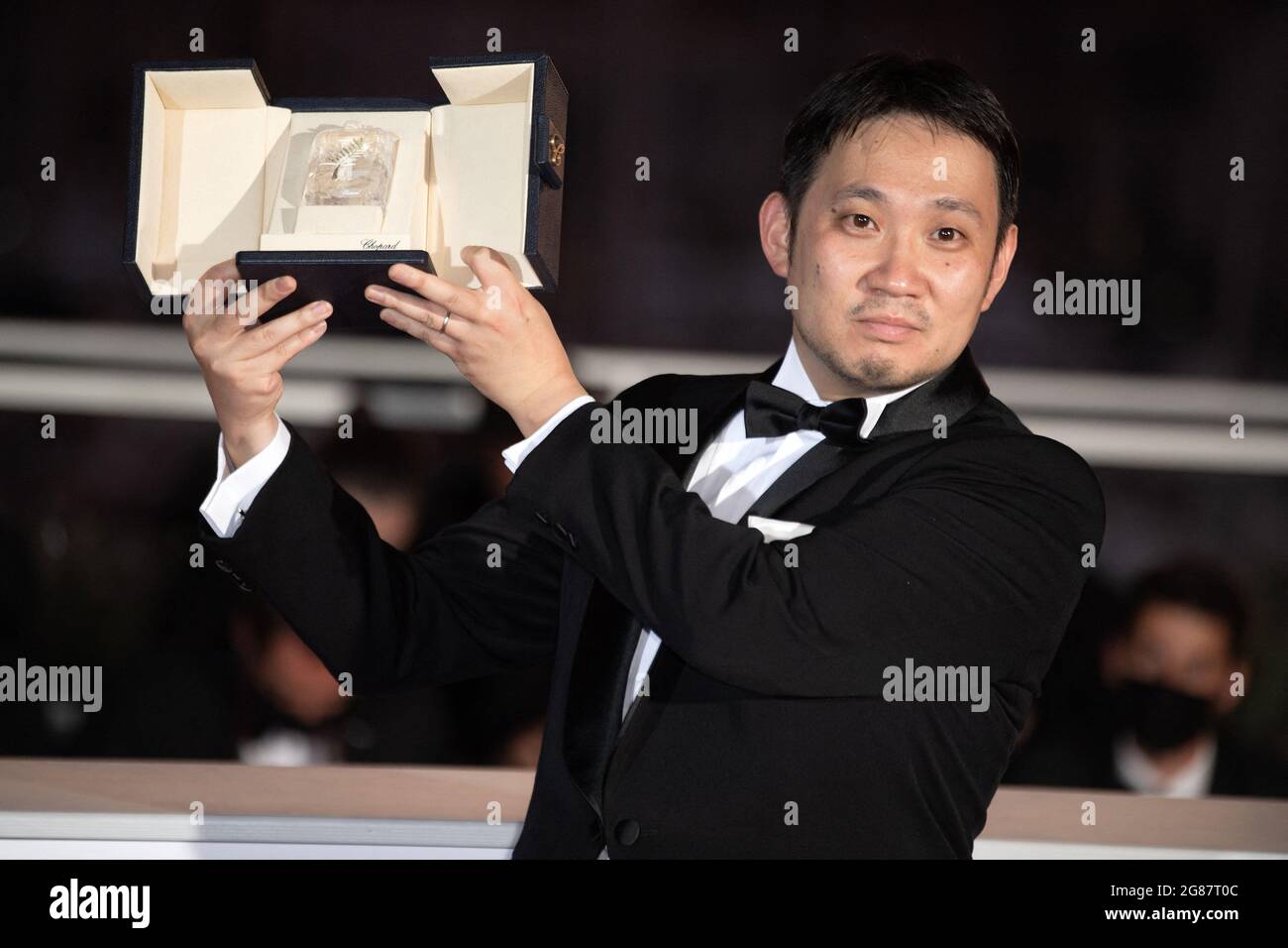 Ryusuke Hamaguchi poses with the Best Screenplay Award for Drive my Car ...