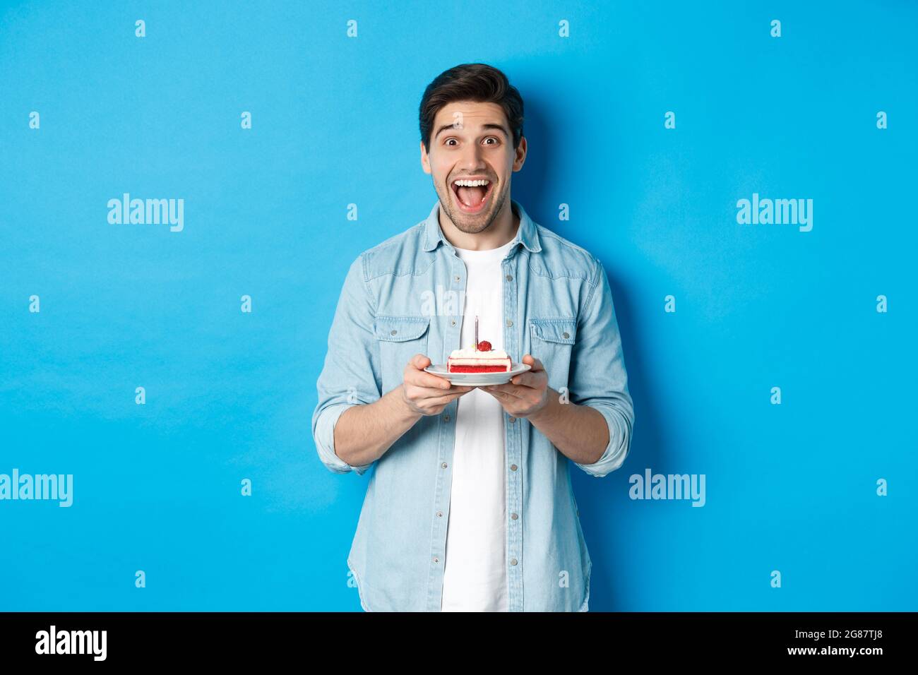 Excited guy holding birthday cake and smiling at camera, celebrating b ...