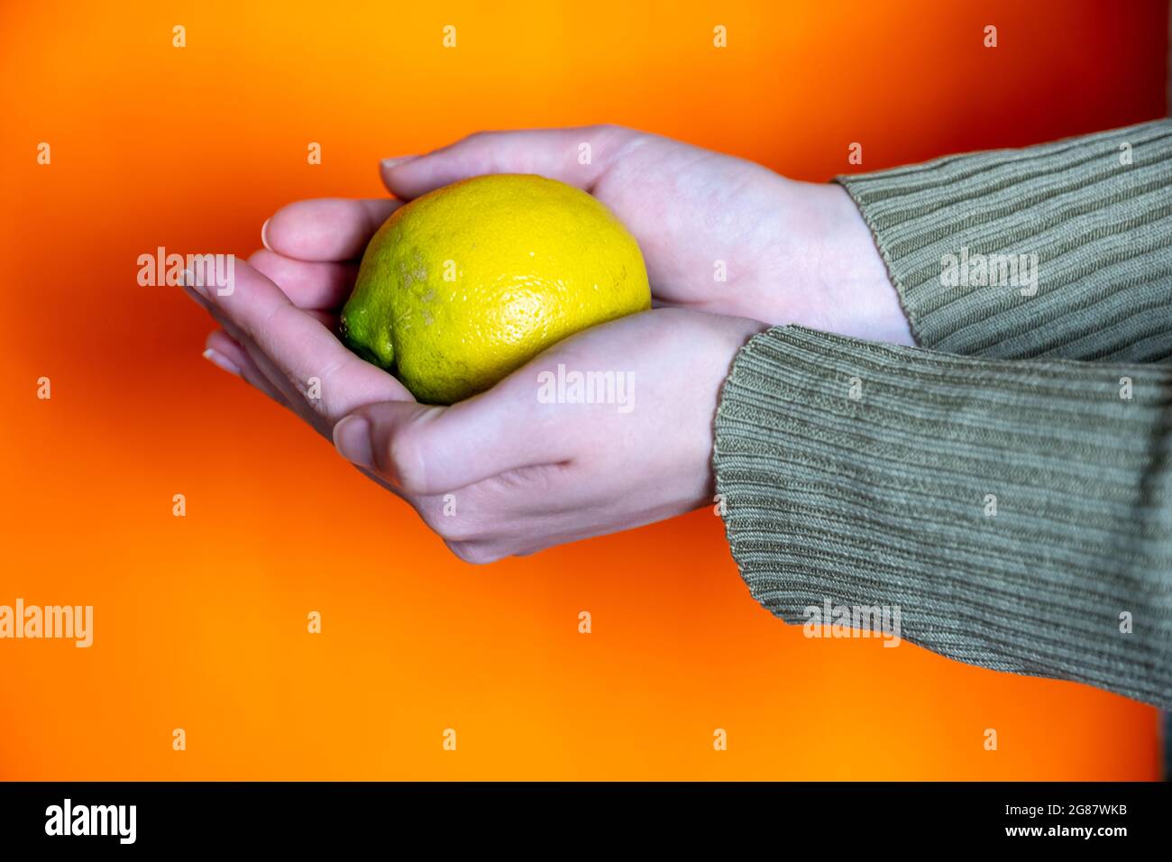 hands holding lemon with orange background Stock Photo - Alamy