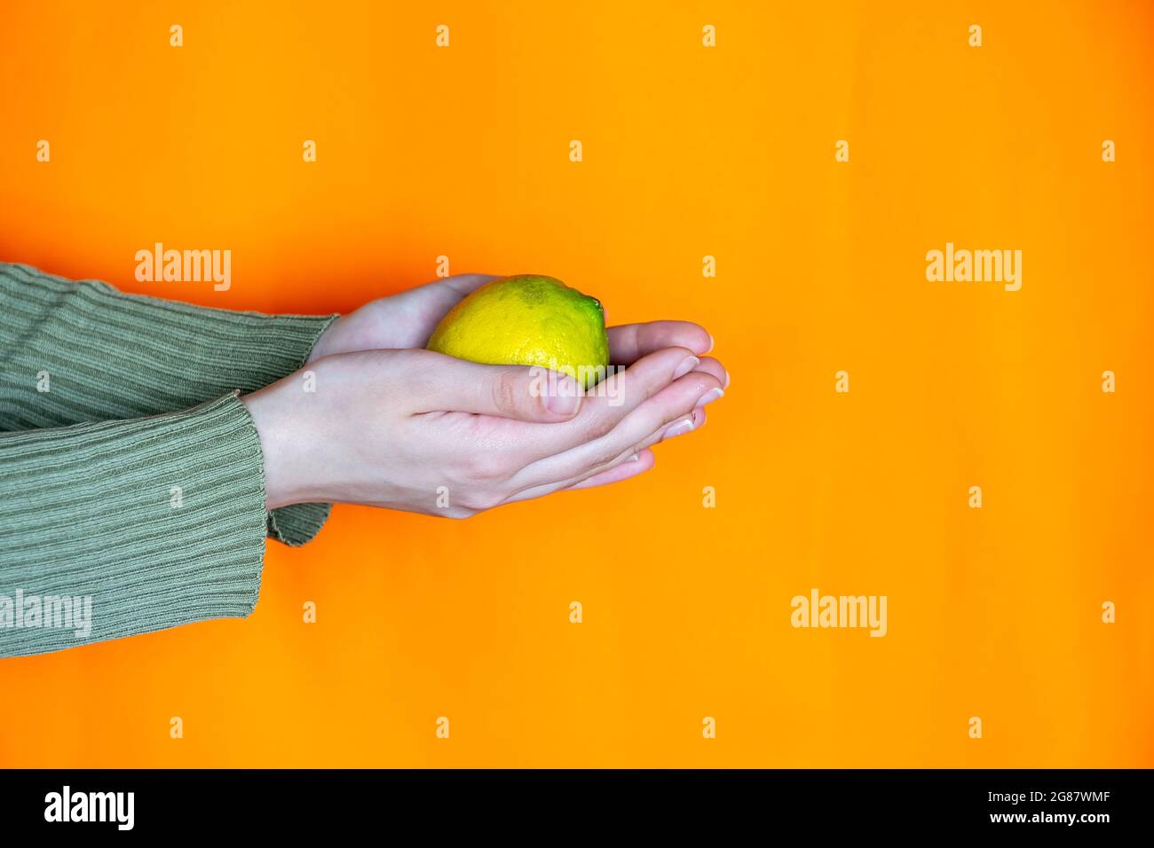 hands holding lemon with orange background Stock Photo - Alamy