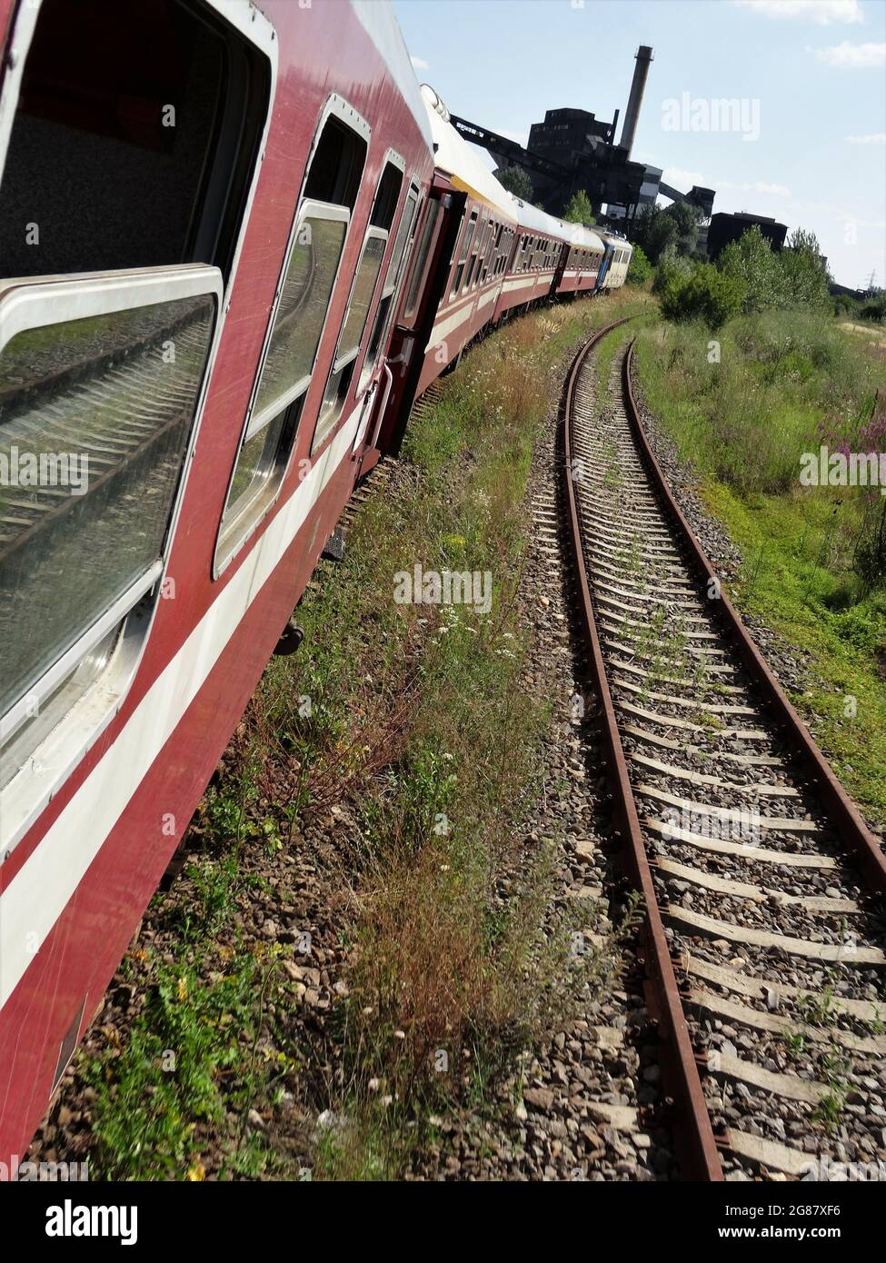 A vertical shot of a train on the rails in a field under the sunlight ...