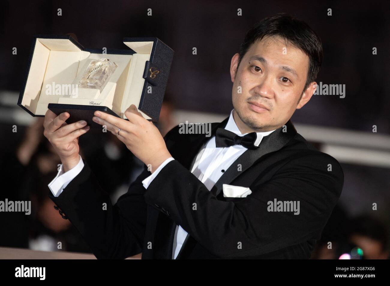Ryusuke Hamaguchi poses with the Best Screenplay Award for Drive my Car ...
