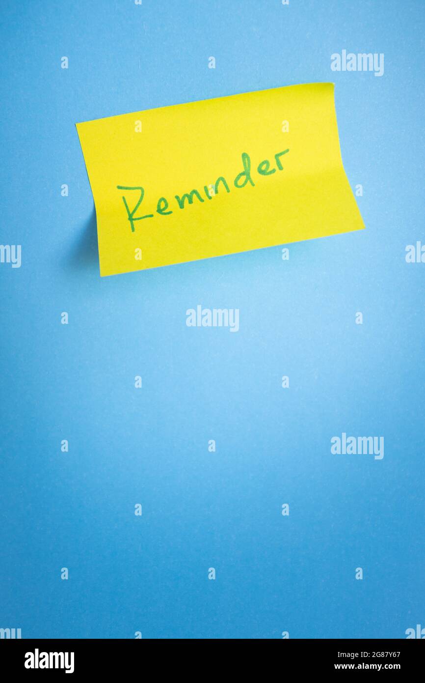Reminder yellow adhesive note on blue light background. Minimalist ...
