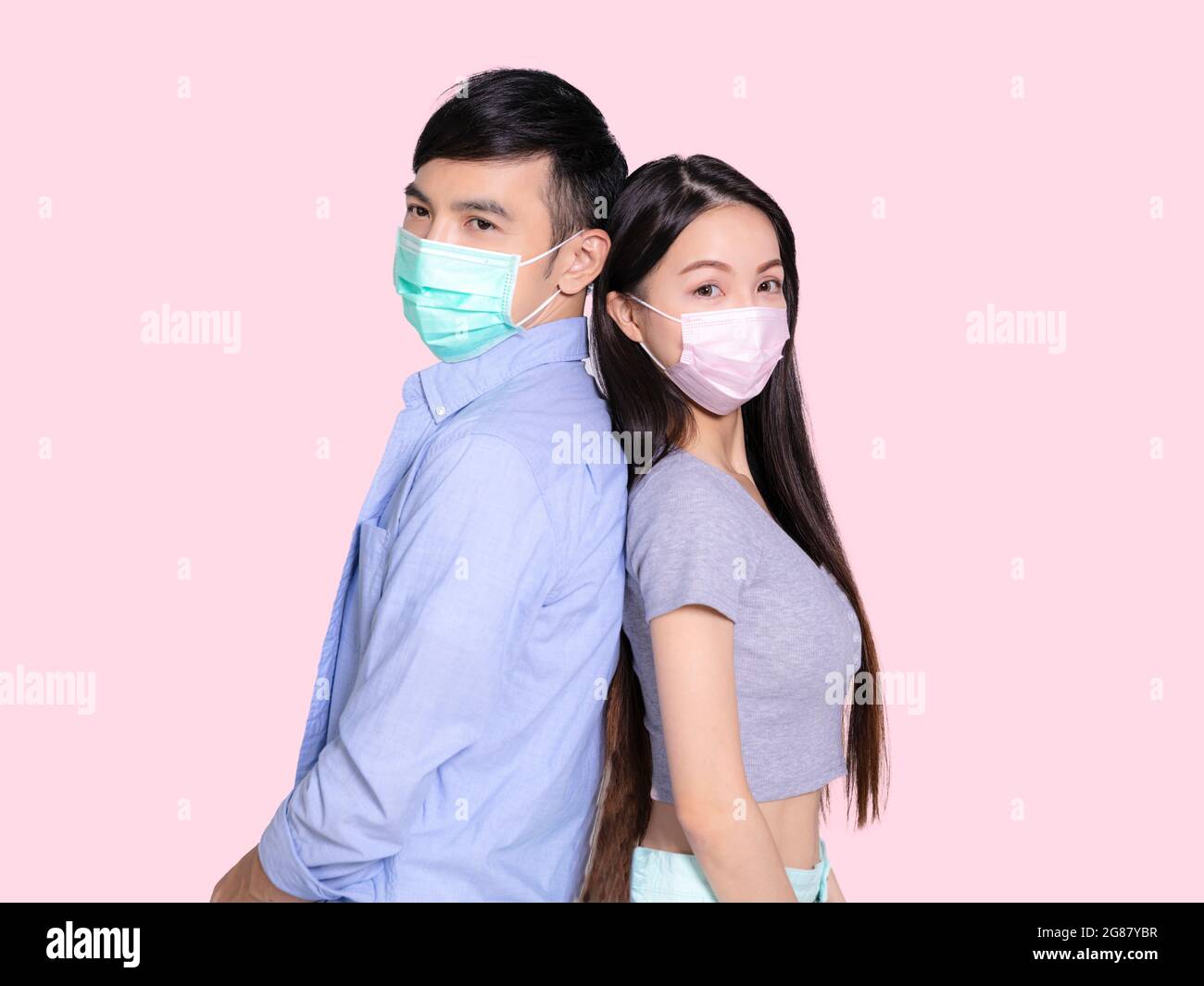 Young couple standing back to back with mask Stock Photo - Alamy