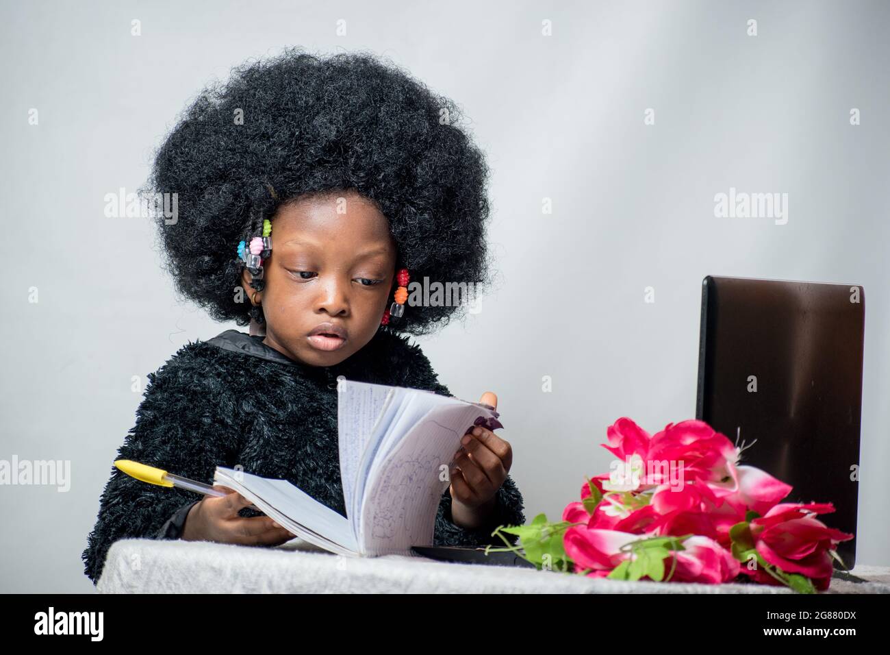 African girl child with afro hair, writing with a pen, studying and ...