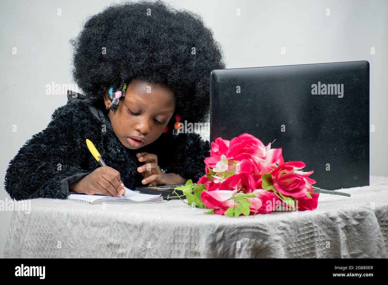 African girl child with afro hair, writing with a pen, studying and ...