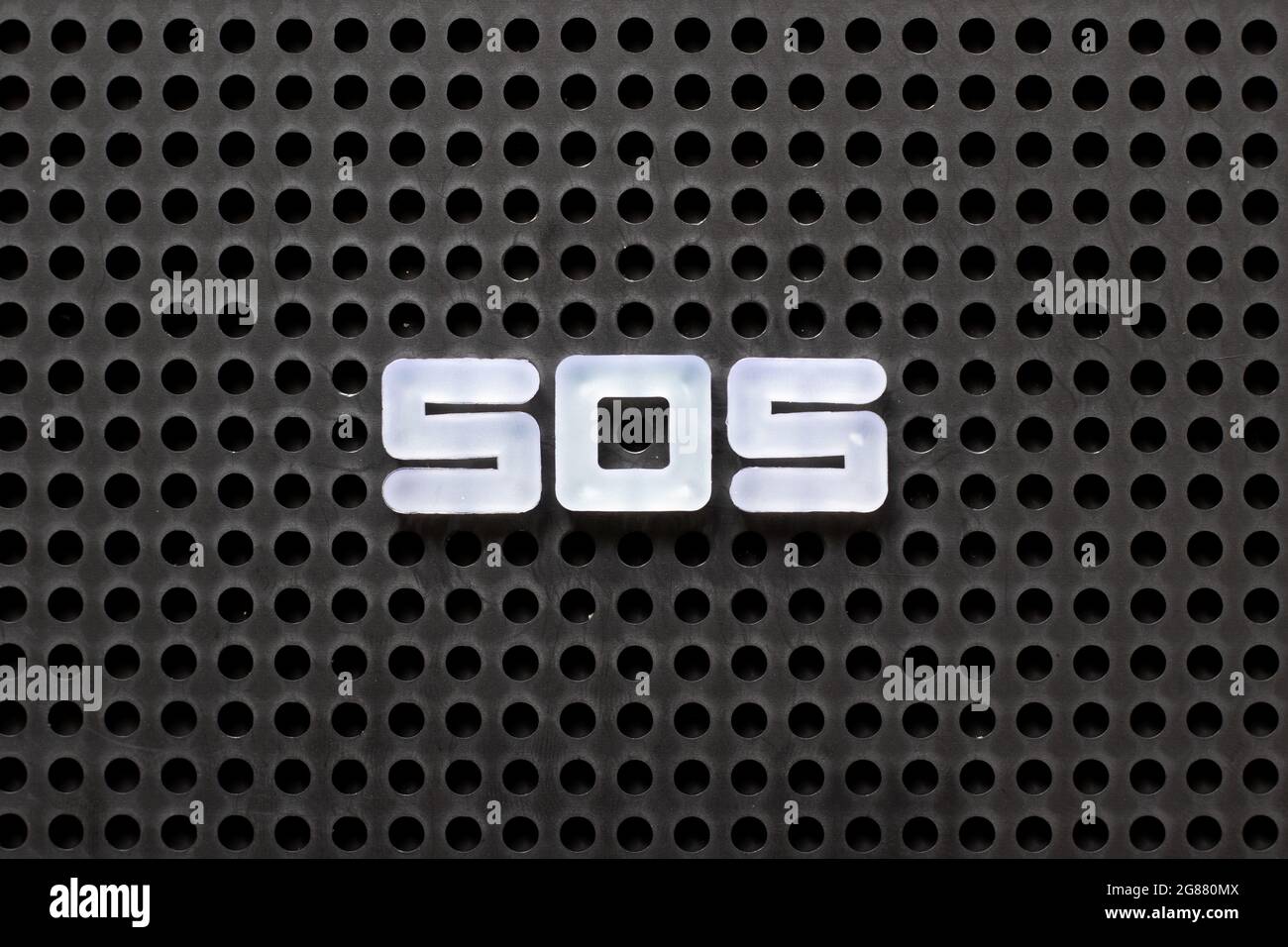 Black color pegboard with white letter in word SOS (abbreviation of ...