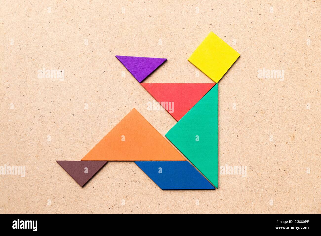Color tangram in sitting man shape on wood background Stock Photo - Alamy