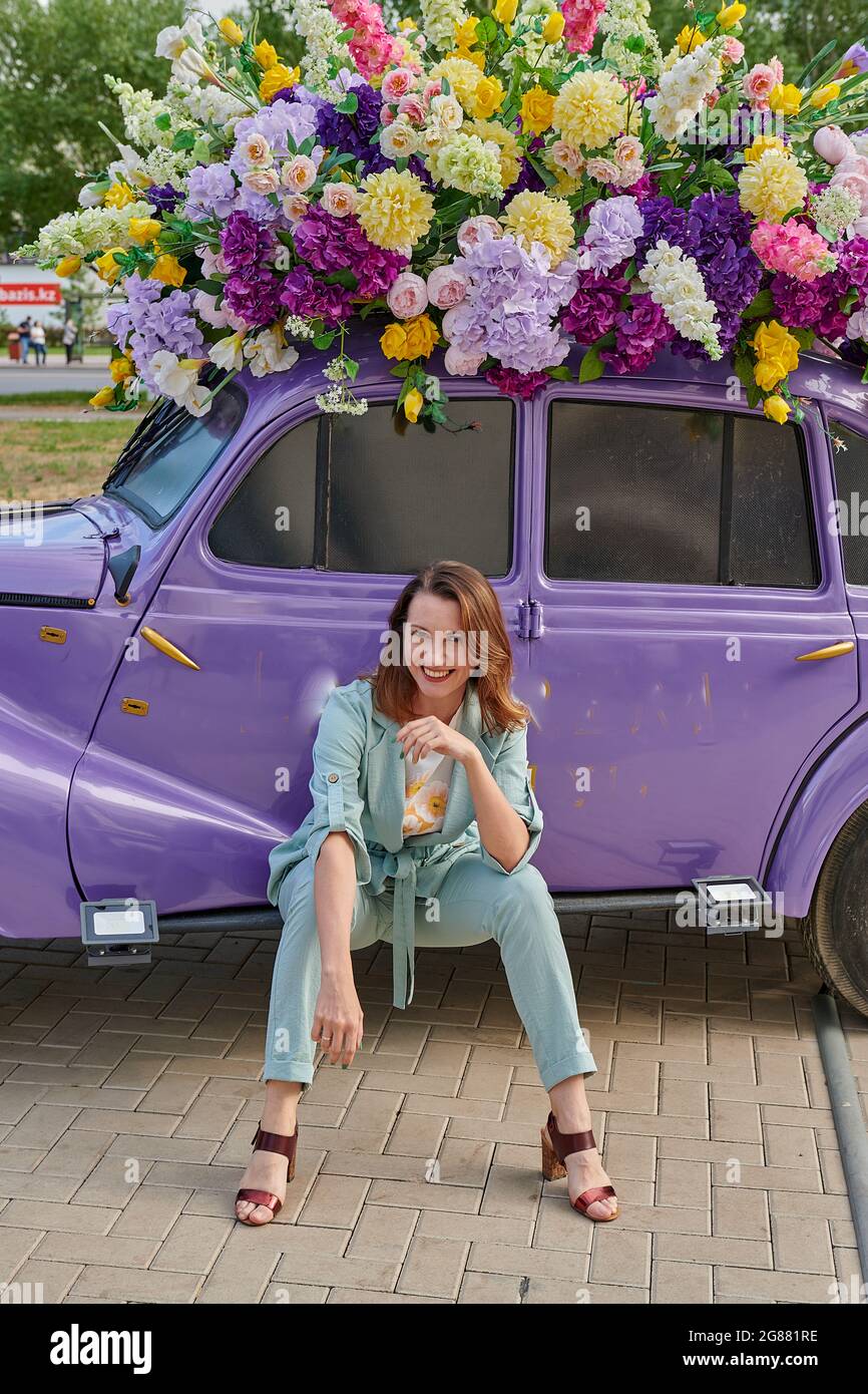 a funny girl in a suit is sitting by the lilac car Stock Photo - Alamy