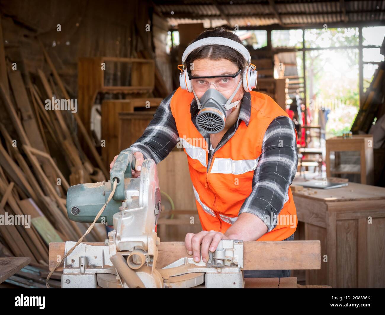 Handsome Caucasian carpenter craftsman wearing safety gear working with ...