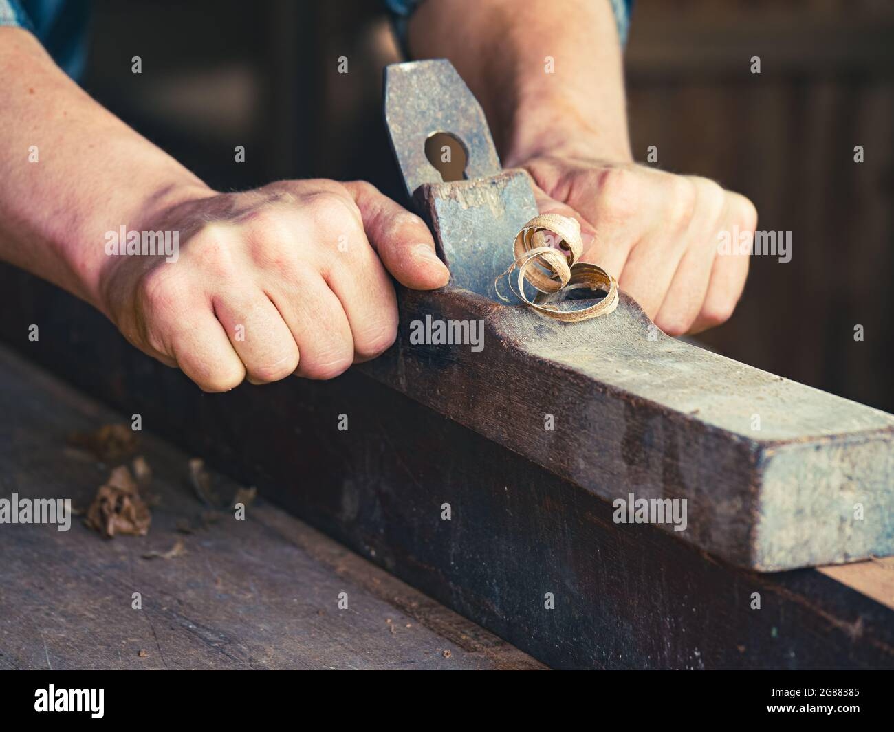 The carpenter using a manual plane for woodworking in his workshop ...