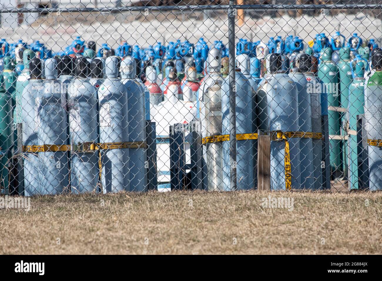 Gas cylinders stored behind wire mesh fence in factory Stock Photo - Alamy