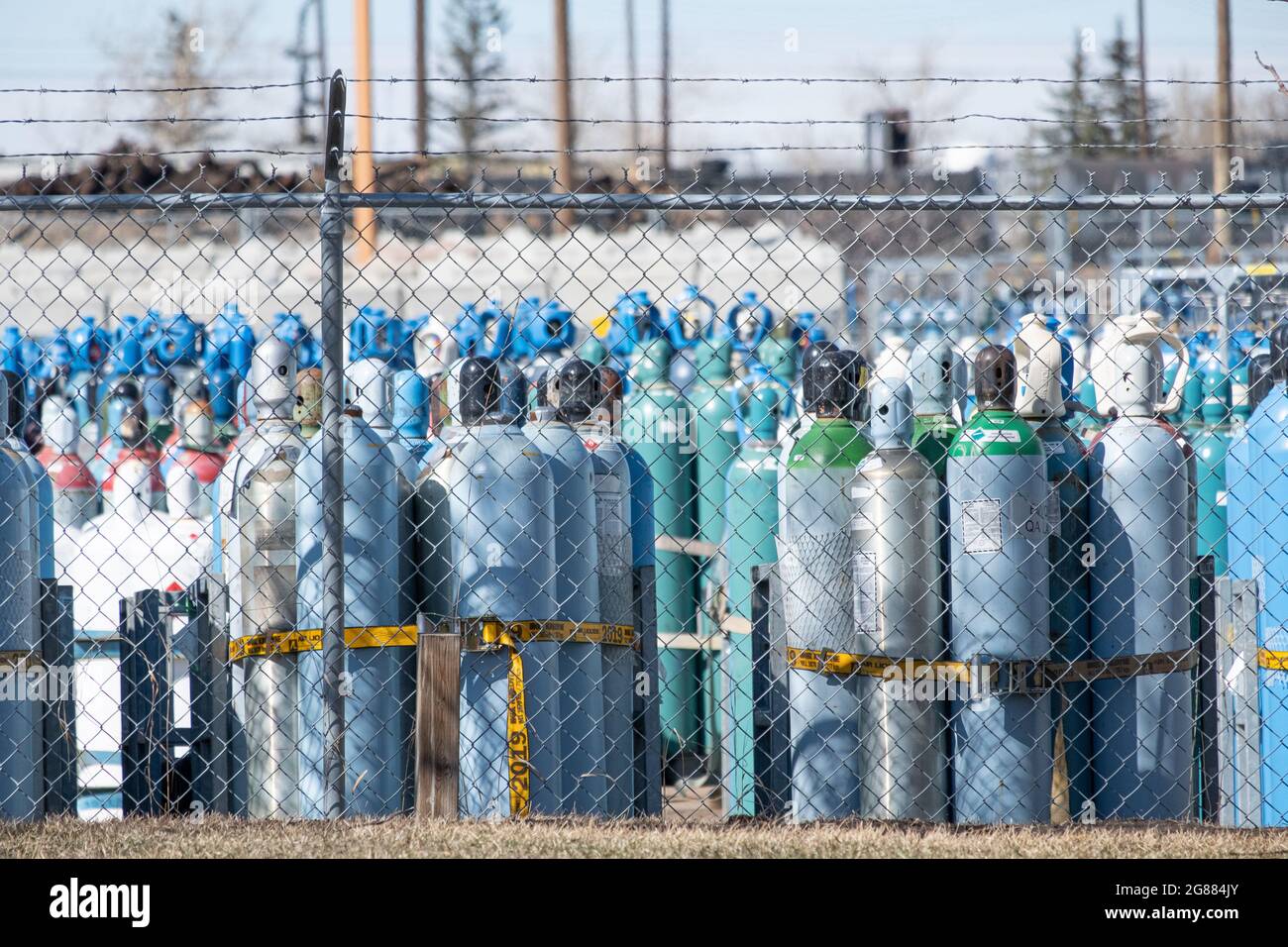Gas cylinders stored behind wire mesh fence in factory Stock Photo - Alamy