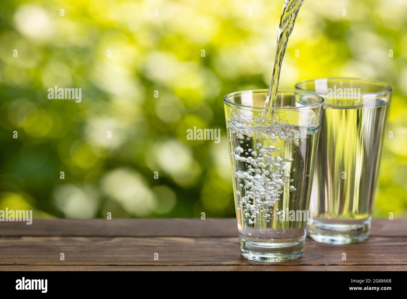 water pouring into glass on table outdoors Stock Photo - Alamy