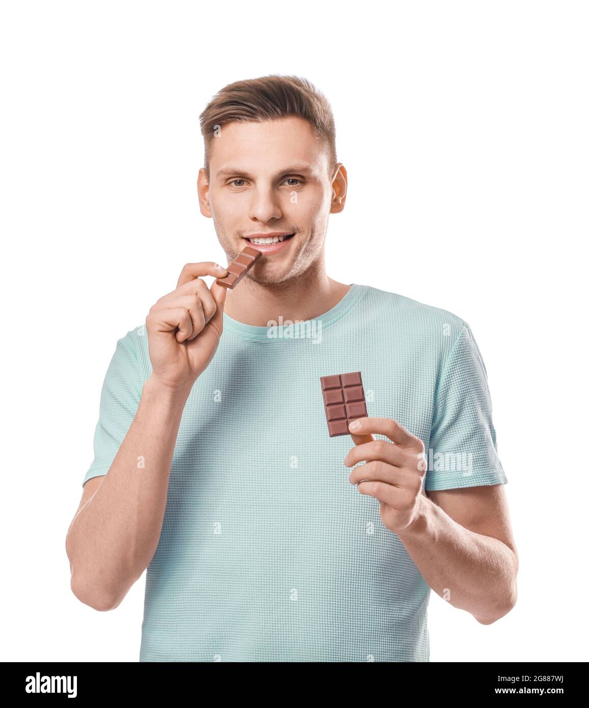 Handsome young man eating tasty chocolate on white background Stock ...