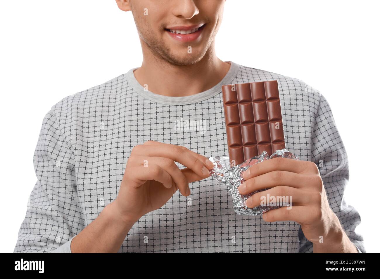 Handsome young man eating tasty chocolate on white background Stock ...