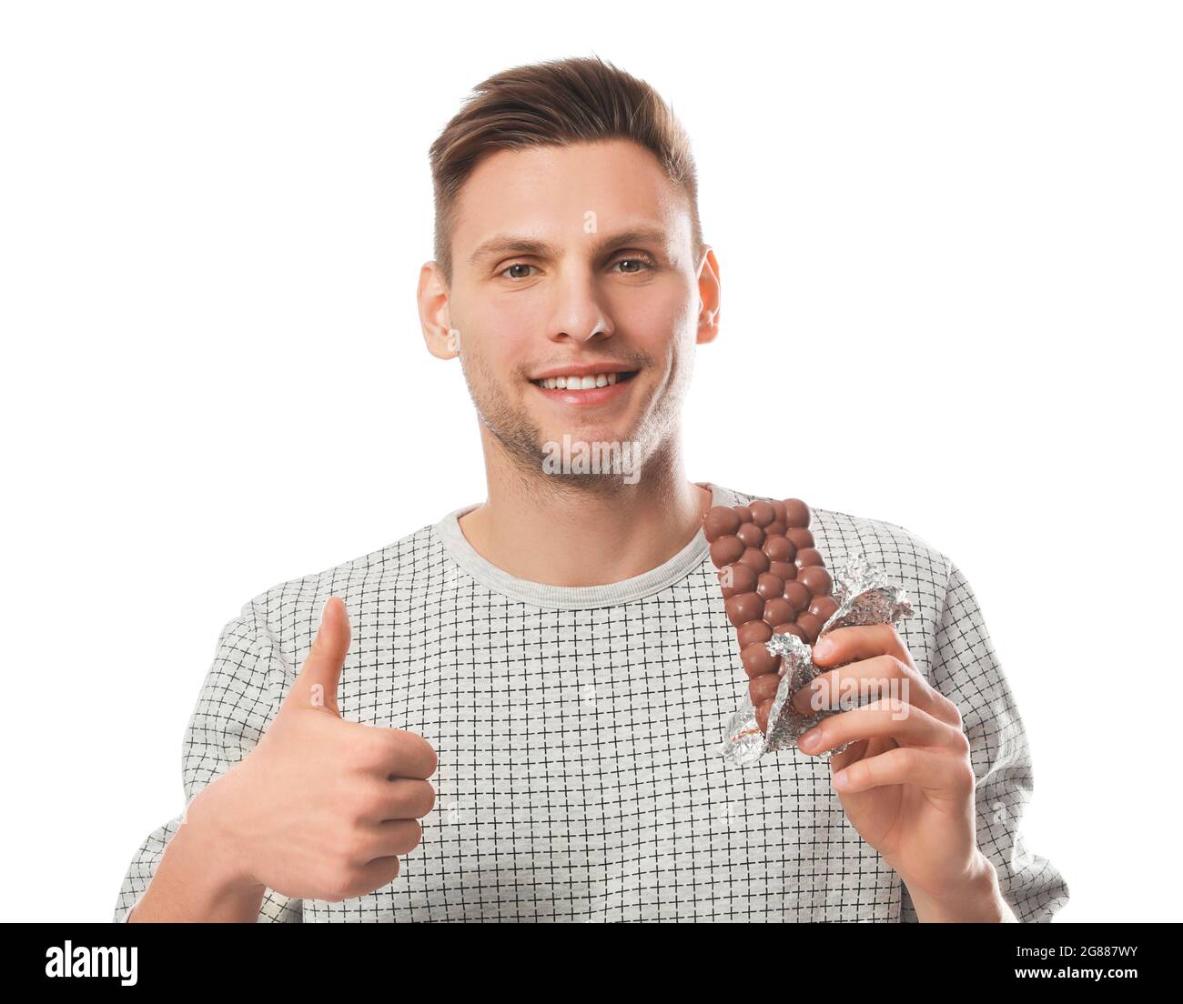 Handsome young man with tasty chocolate showing thumb-up on white ...