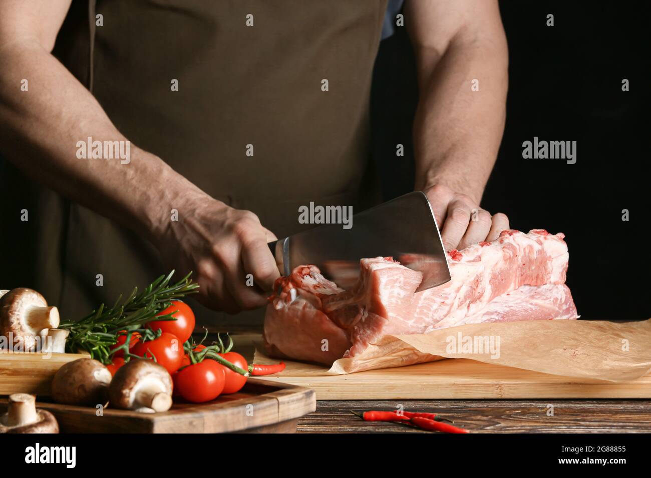Man cutting raw pork ribs on wooden table Stock Photo - Alamy