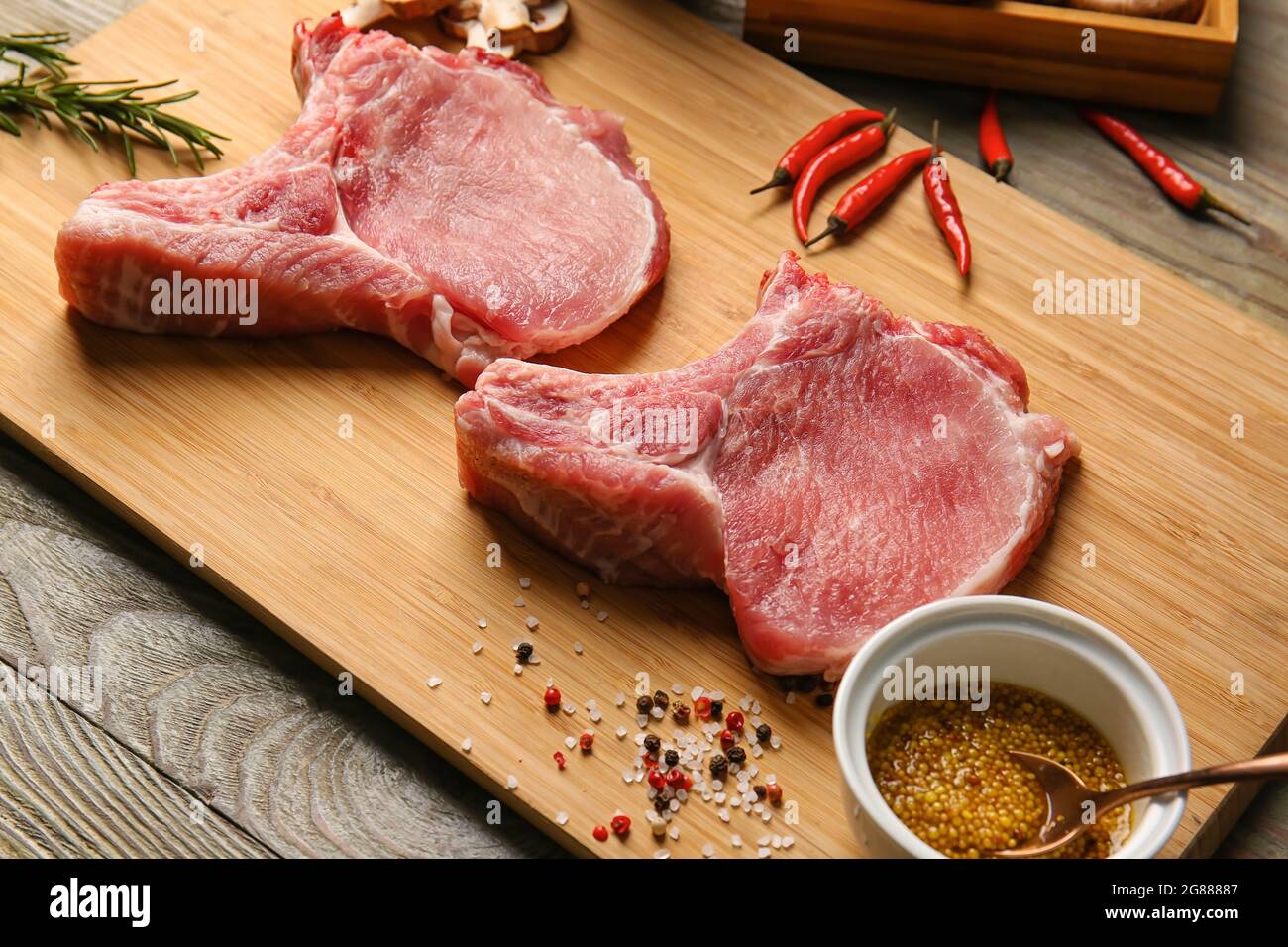 Board with slices of raw pork ribs and spices on wooden background ...