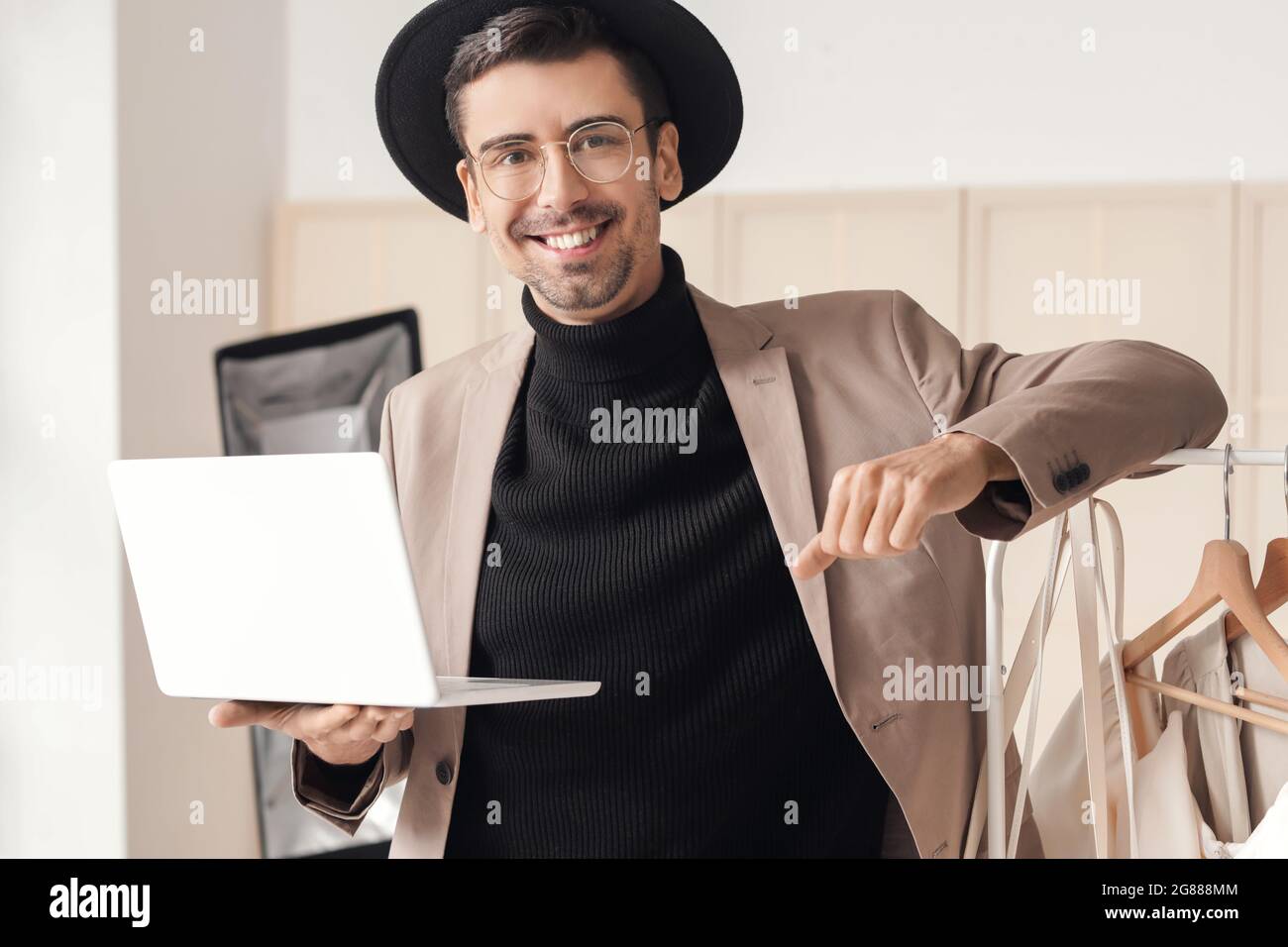 Male stylist working with laptop in studio Stock Photo - Alamy