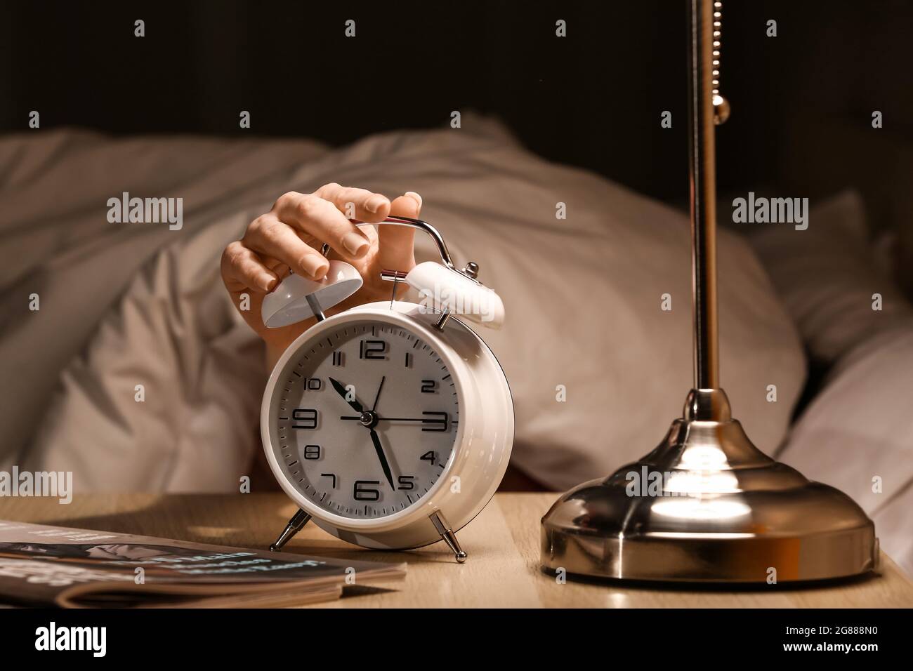 Woman turning off alarm clock in bedroom at night, closeup Stock Photo ...