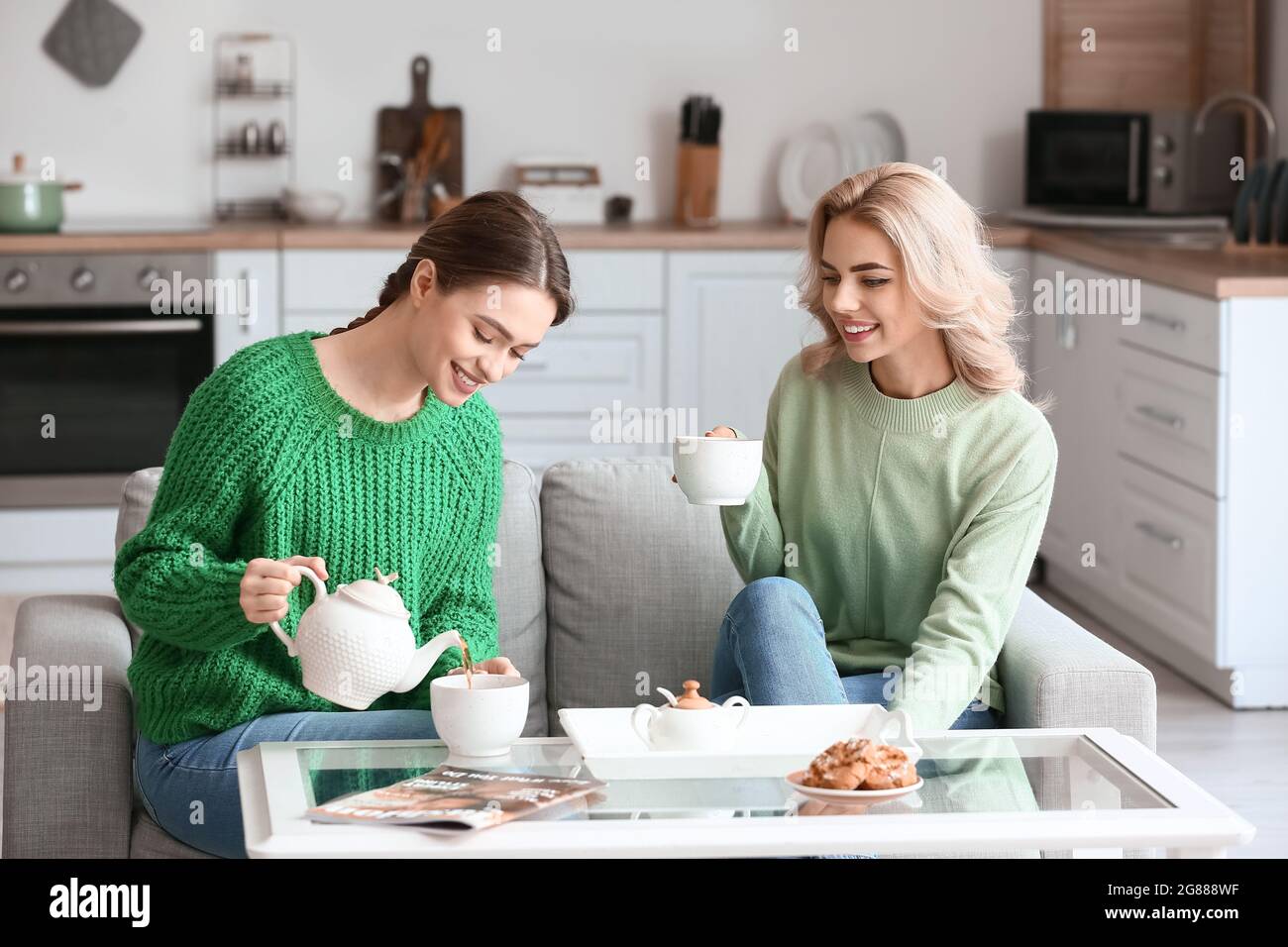 Beautiful young sisters drinking tea at home Stock Photo - Alamy