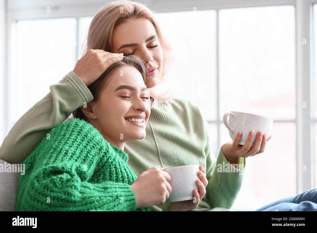 Beautiful young sisters drinking tea at home Stock Photo - Alamy