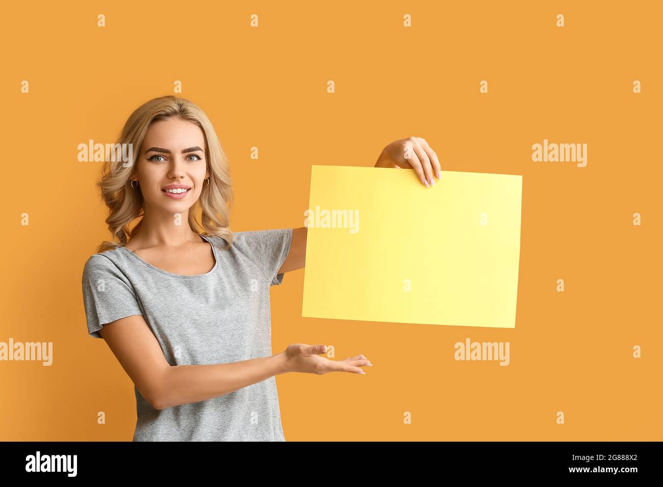 Beautiful young woman with blank paper sheet on color background Stock ...