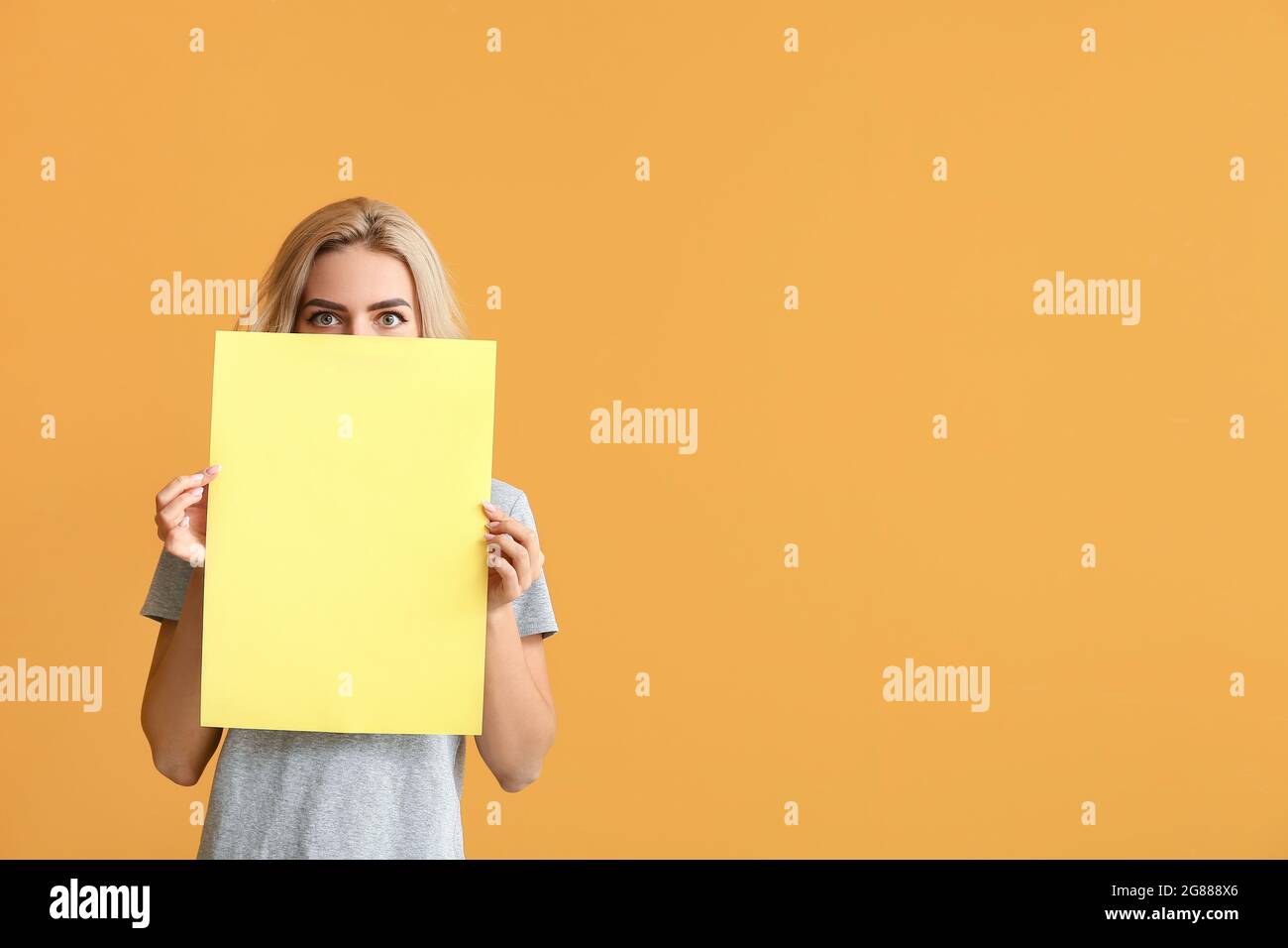 Young woman with blank paper sheet on color background Stock Photo - Alamy