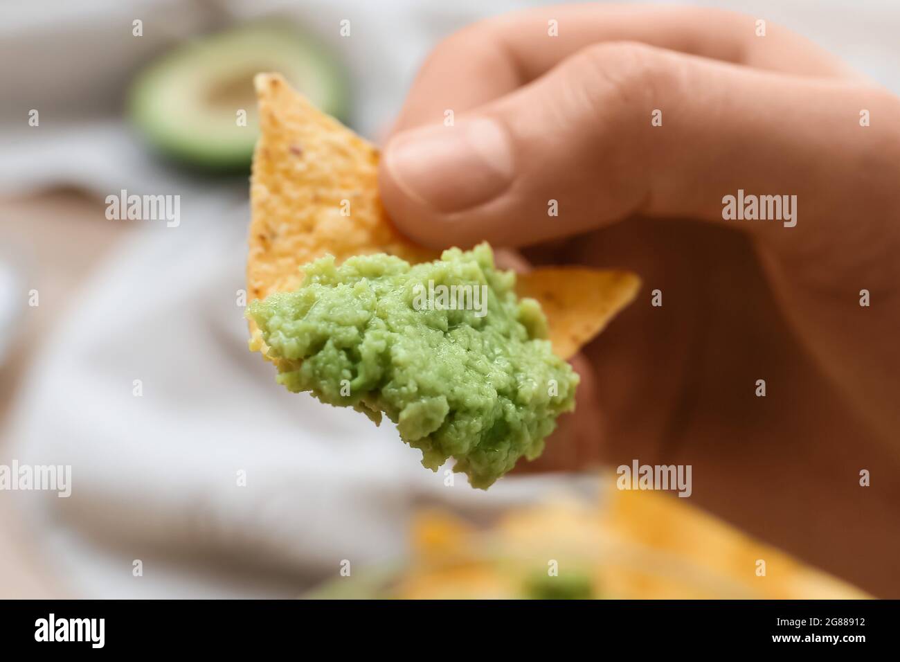 Woman eating tasty guacamole with nacho, closeup Stock Photo - Alamy