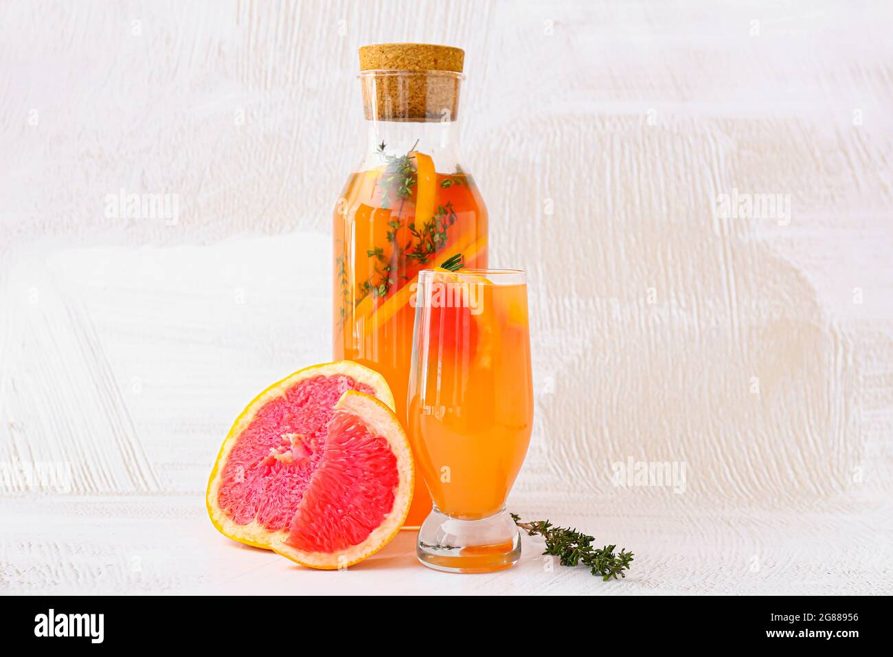 Glass and bottle of tasty grapefruit juice on light background Stock ...