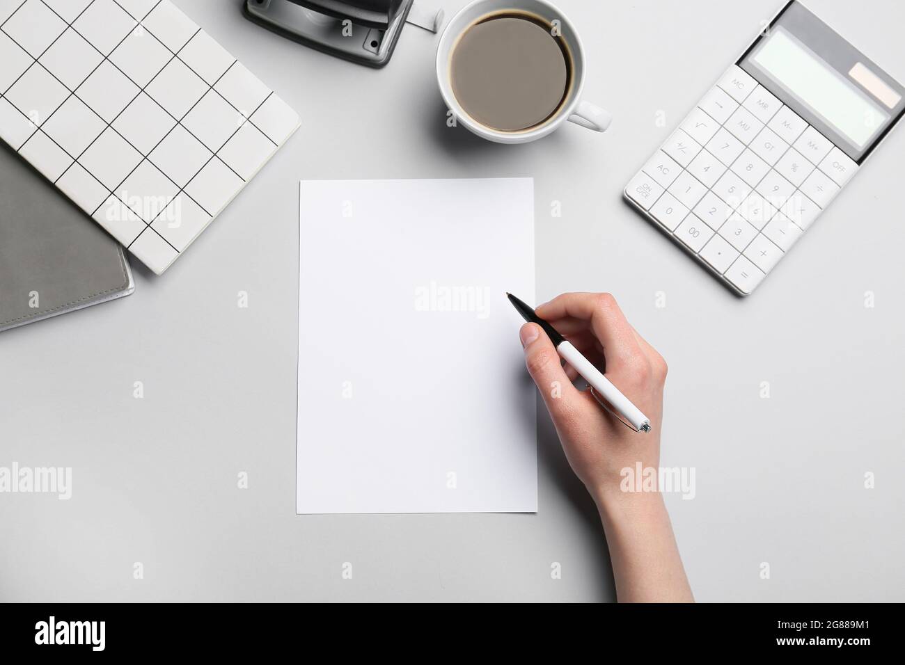 Female hand with blank sheet of paper, pen, cup of coffee and ...