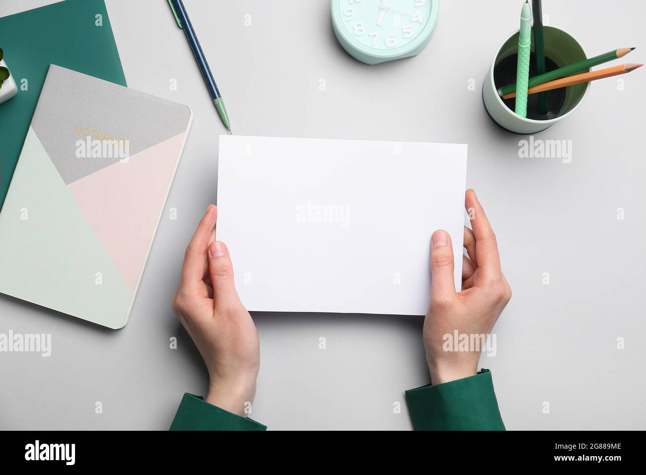 Female hands with blank sheet of paper, alarm clock and stationery on ...