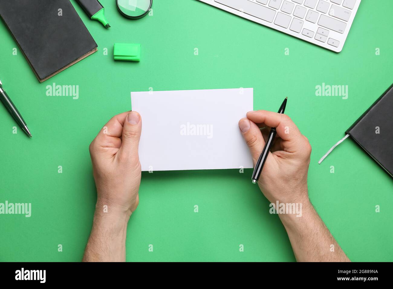 Male hands with blank sheet of paper, stationery and keyboard on color ...