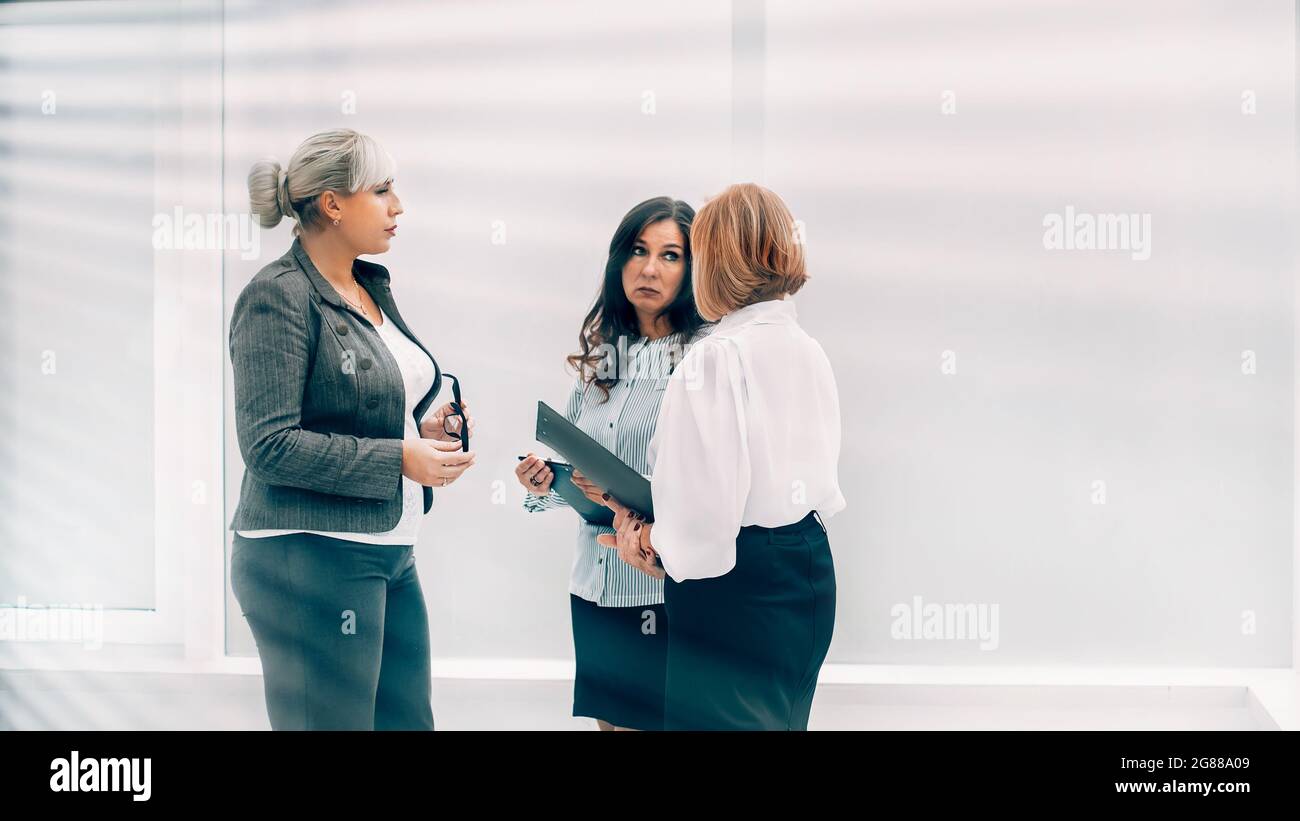 through the blinds. a group of business women talking in the office ...