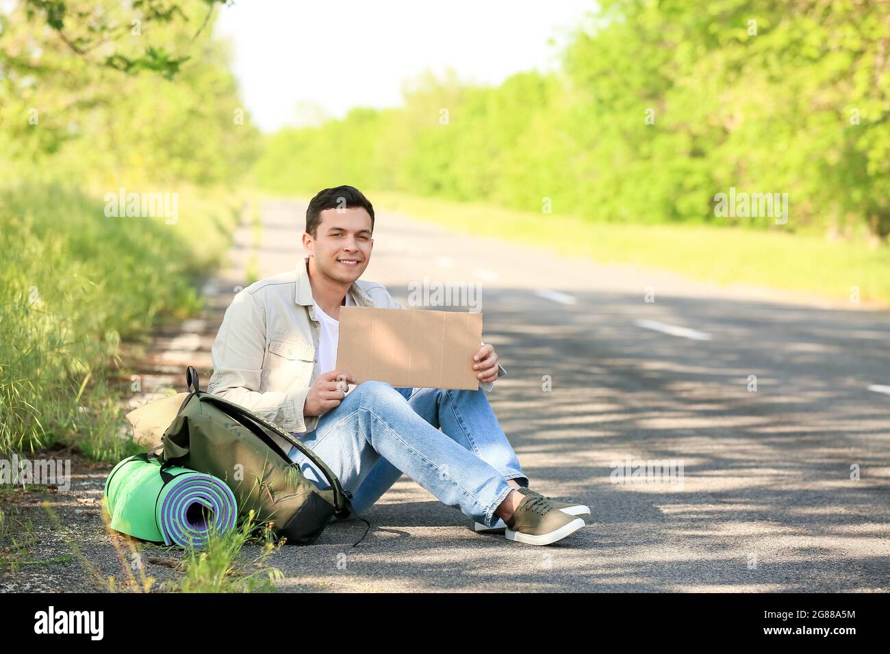 Young man hitchhiking roadside hi-res stock photography and images - Alamy