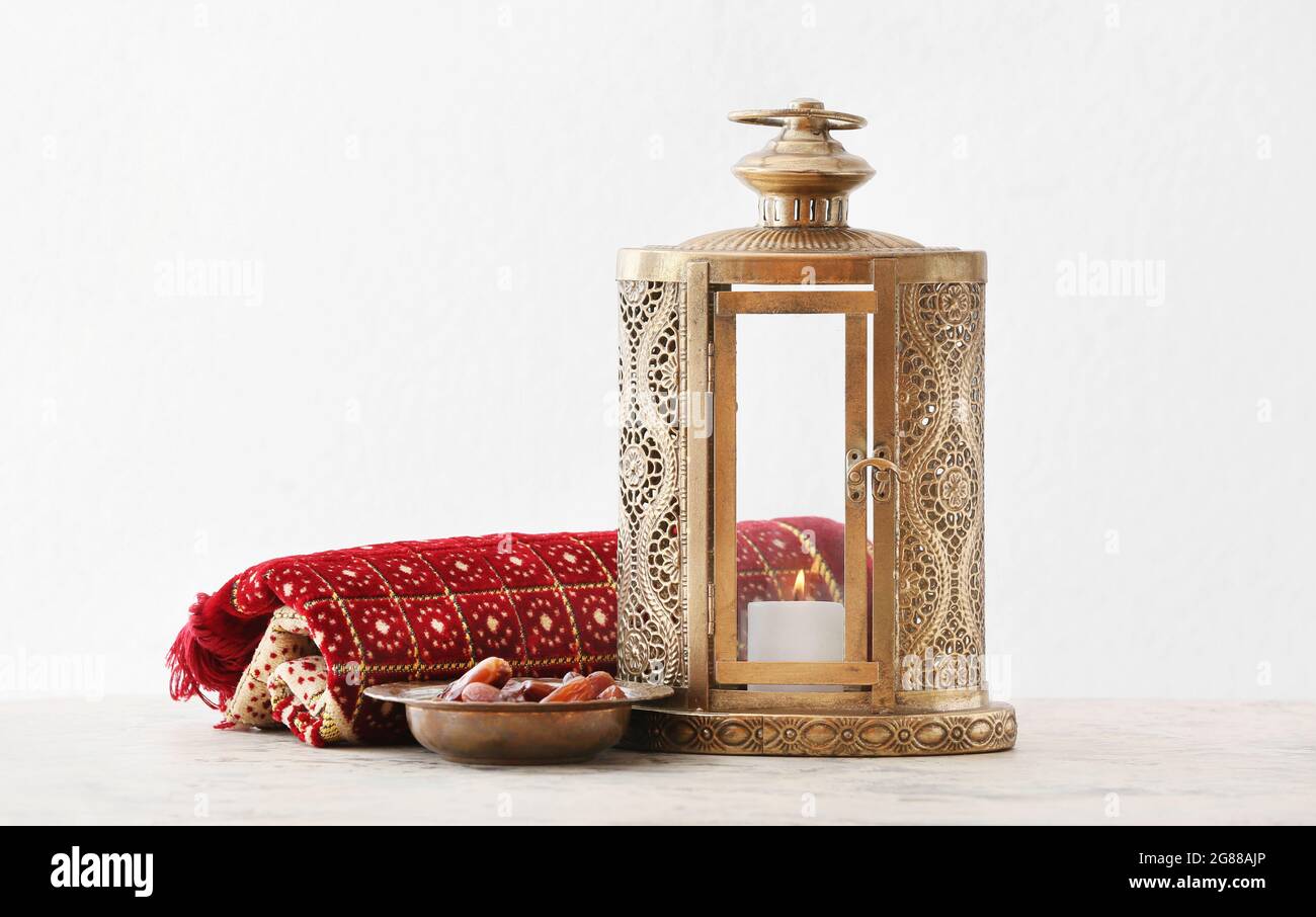 Muslim lantern with prayer rug and dates on light background Stock ...