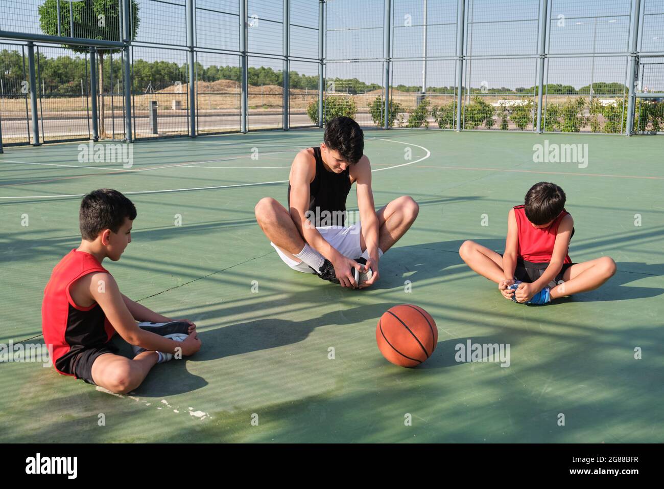 Three brothers doing leg stretching exercises. Siblings stretching ...