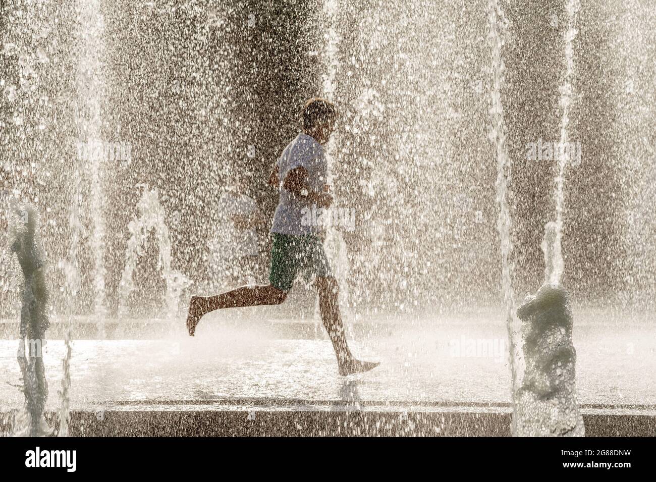 Silhouette of a dressed adult man running through a water fountain in ...