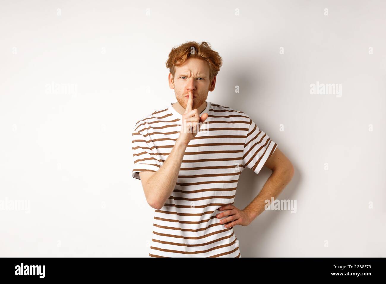 Angry redhead man looking displeased and hushing at camera, making shh ...